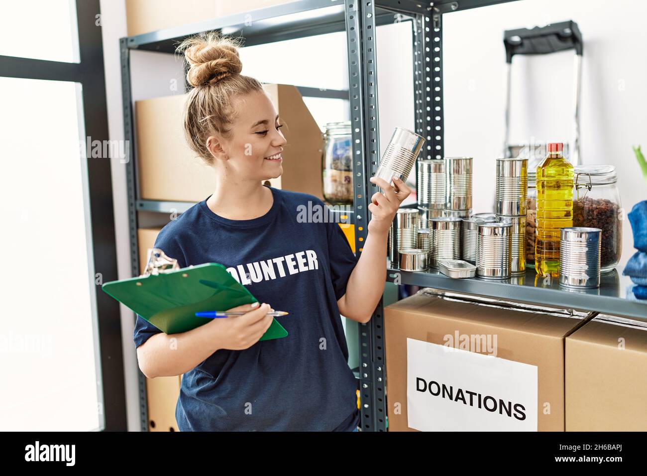 Young blonde girl wearing volunteer uniform working at charity center ...