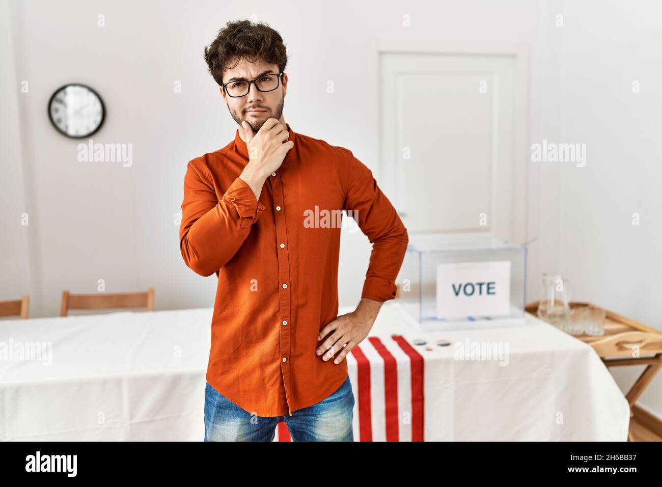 Hispanic man standing by election room looking confident at the camera ...