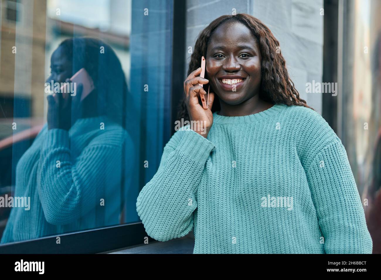 Young african woman smiling happy speaking on the phone leaning on the ...