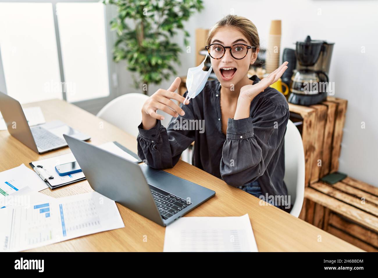 Young blonde woman working at the office wearing safety mask ...