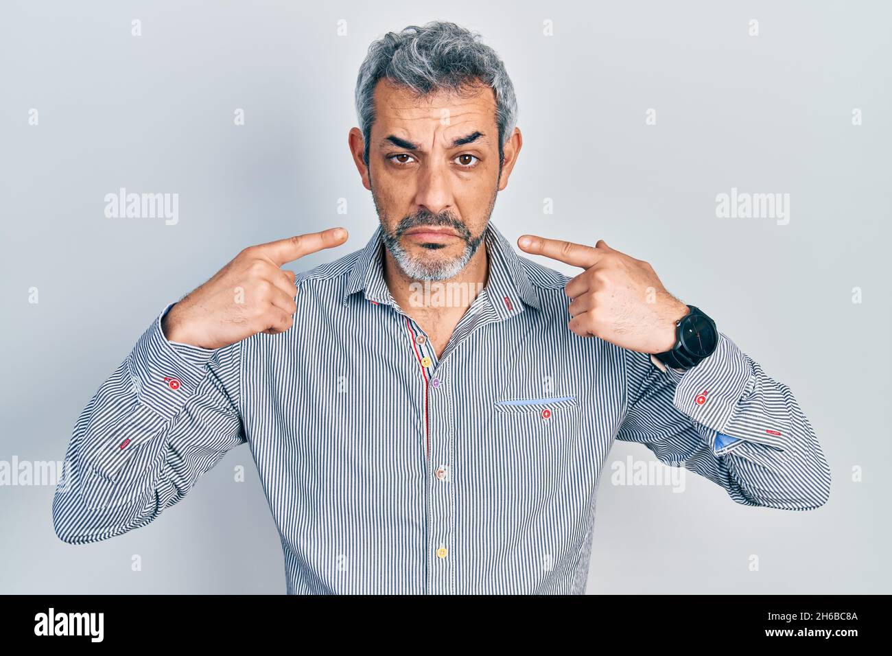 Handsome middle age man with grey hair pointing mouth with fingers ...