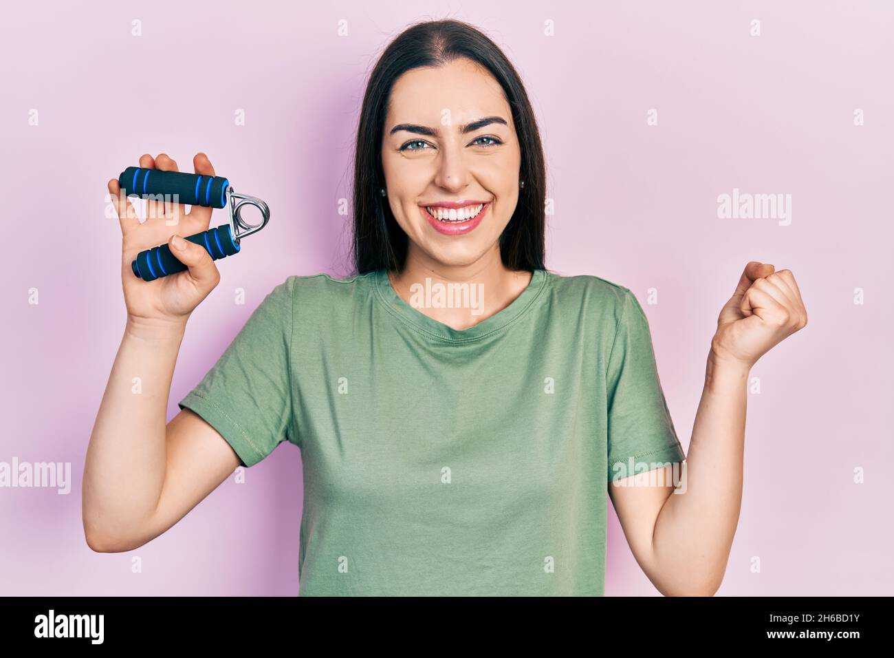 Beautiful woman with blue eyes training muscle with hand grip screaming ...