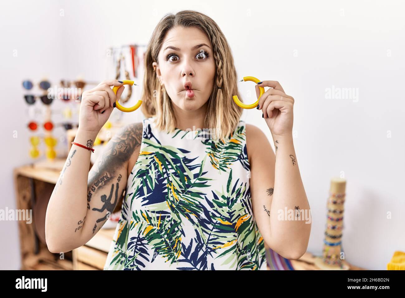Young hispanic customer woman holding earrings at store making fish ...