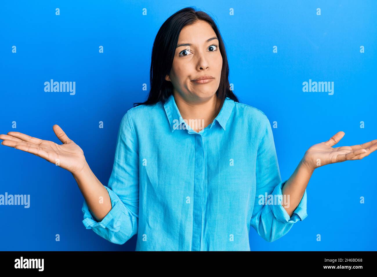 Young latin woman wearing casual clothes clueless and confused with ...
