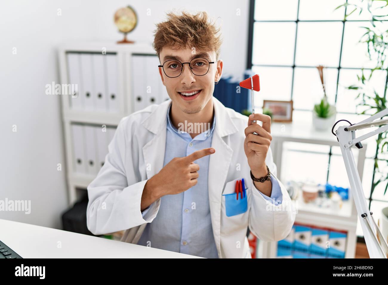 Young caucasian doctor man holding reflex hammer at the clinic smiling ...