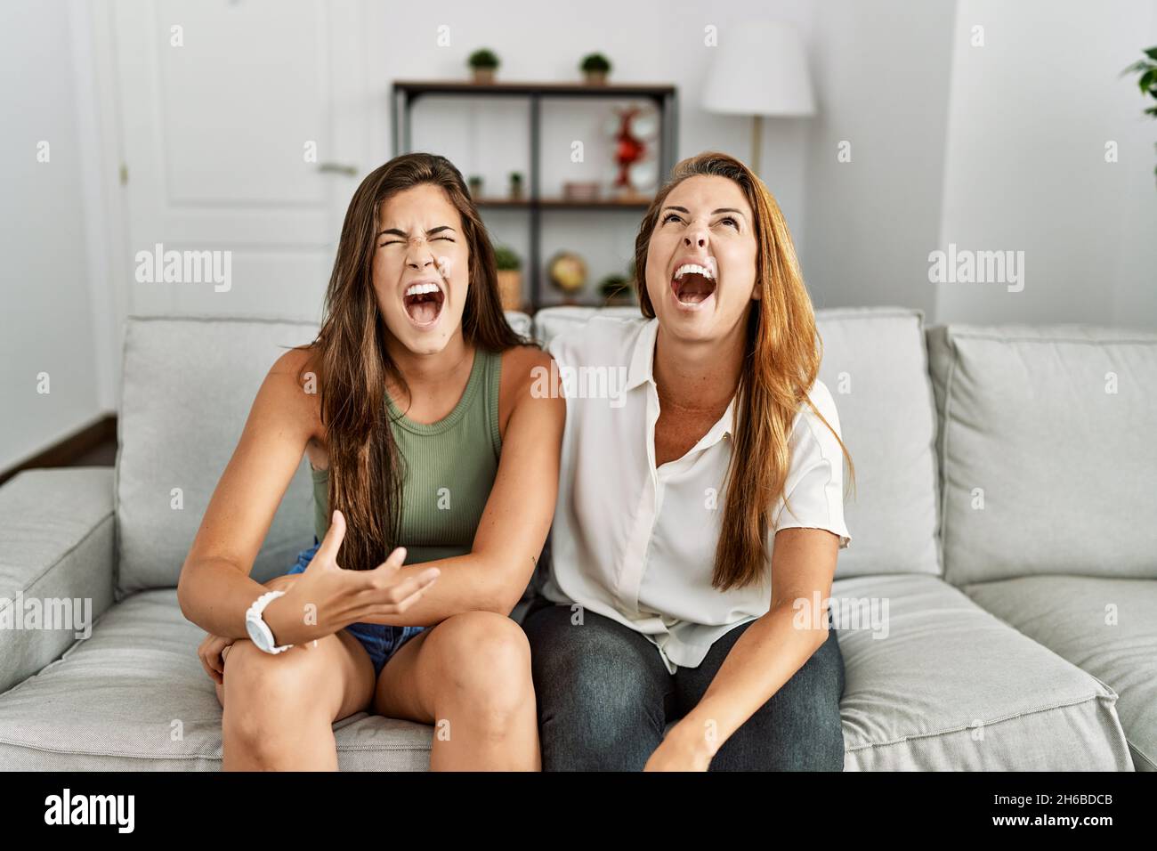 Mother and daughter together sitting on the sofa at home angry and mad ...