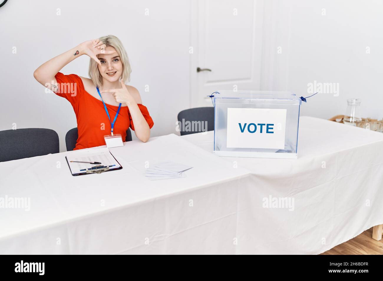 Young caucasian woman at political election sitting by ballot smiling ...