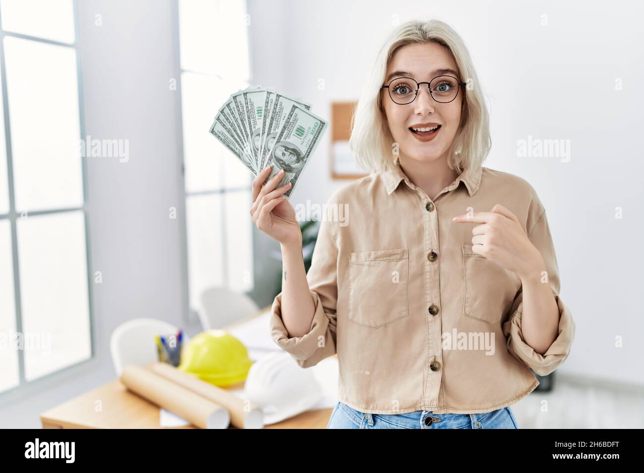 Young beautiful caucasian woman at construction office holding money ...