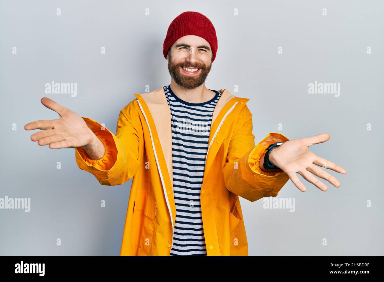 Caucasian man with beard wearing yellow raincoat smiling cheerful ...