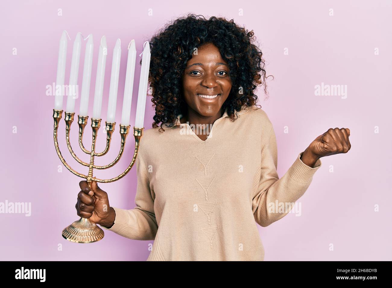 Young african american woman holding menorah hanukkah jewish candle ...
