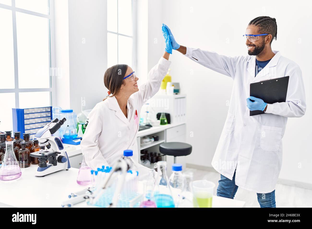 Man and woman scientist partners holding clipboard high five raised up ...