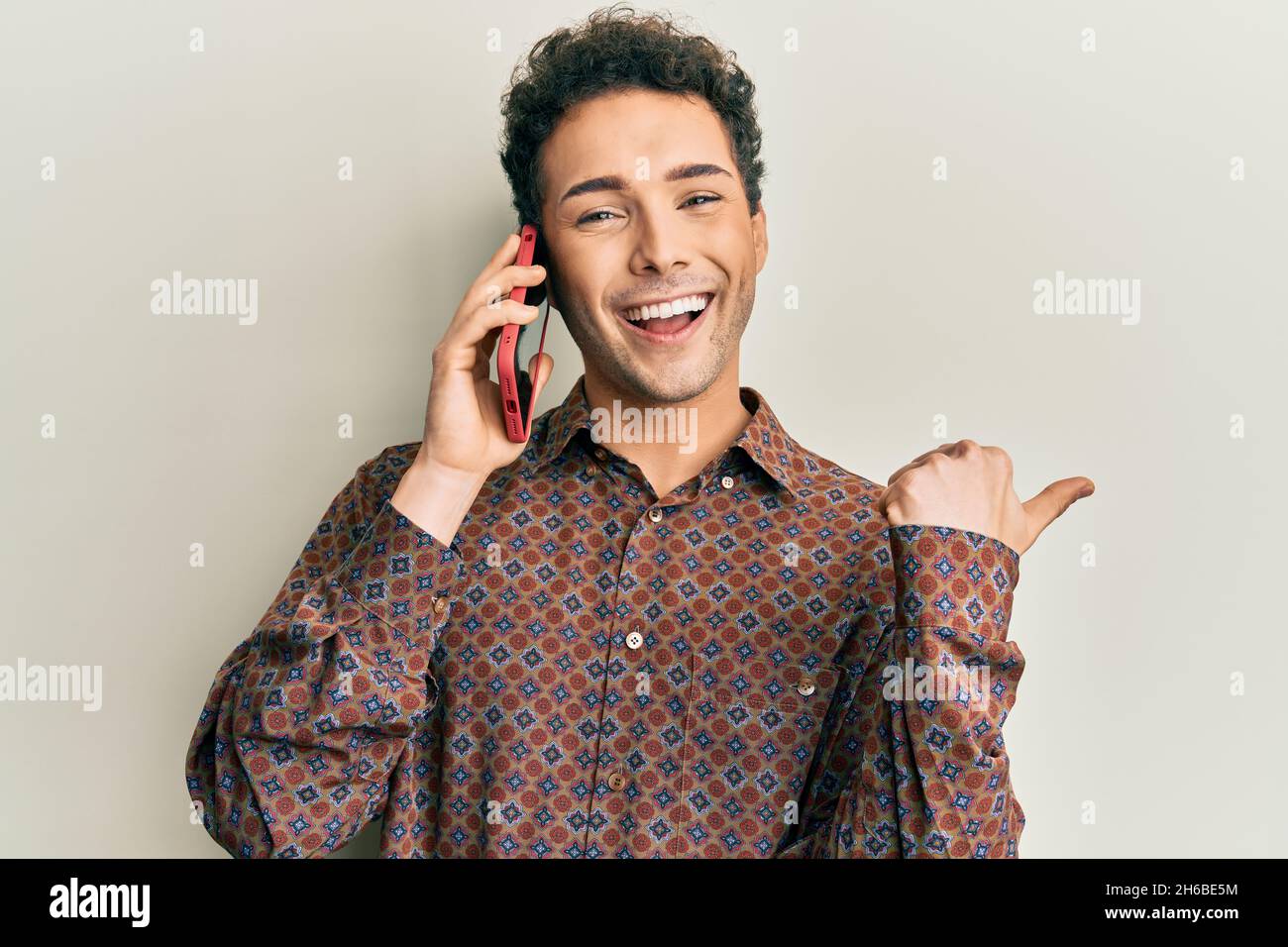 Young handsome man having conversation talking on the smartphone ...