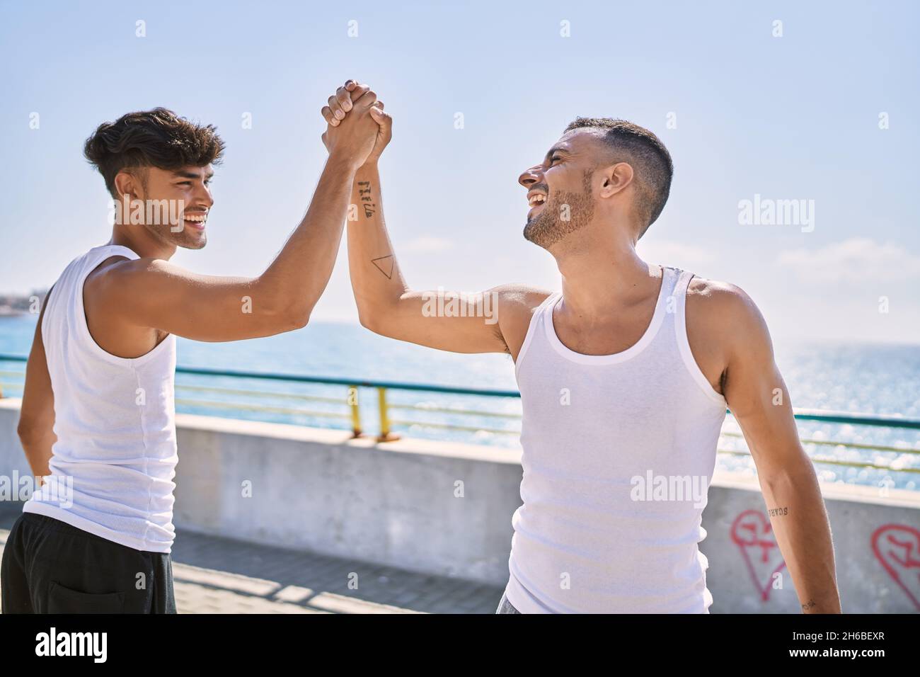 Two hispanic men couple smiling confident high five with hands raised ...