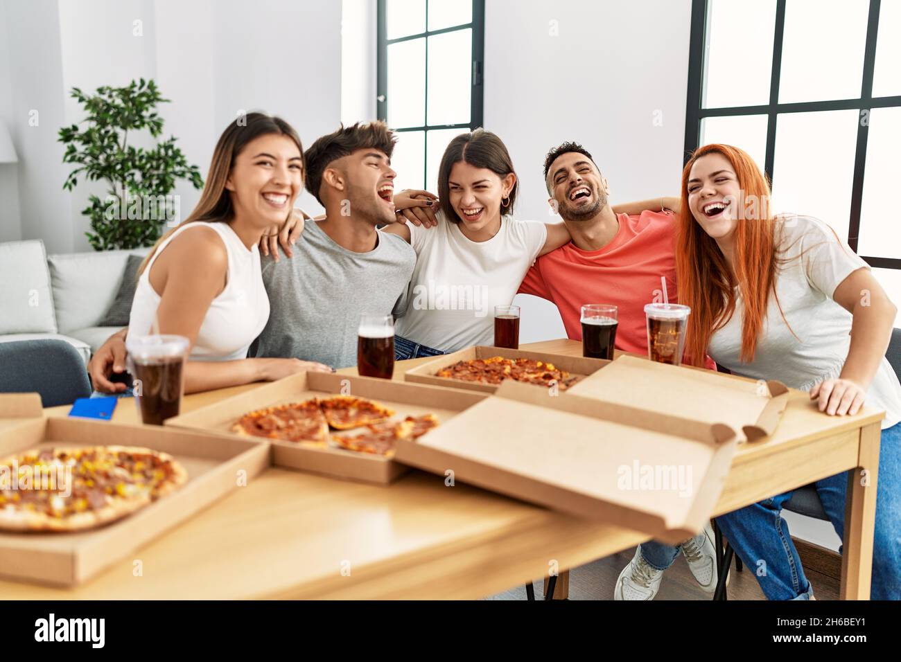 Group of young people smiling happy and hugging eating italian pizza at ...