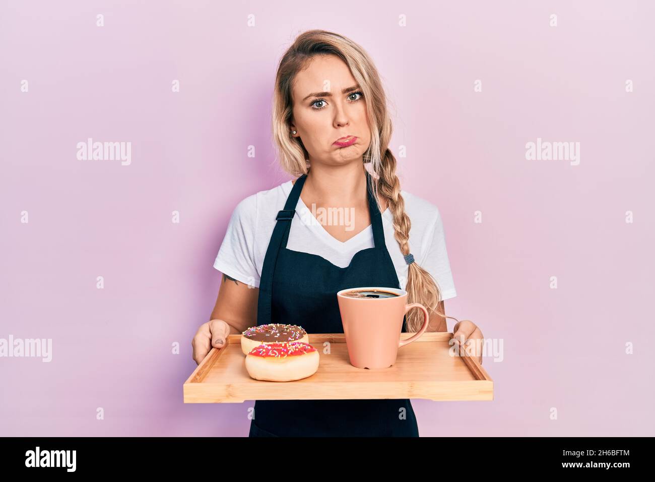Beautiful young blonde woman wearing waitress apron holding breakfast ...