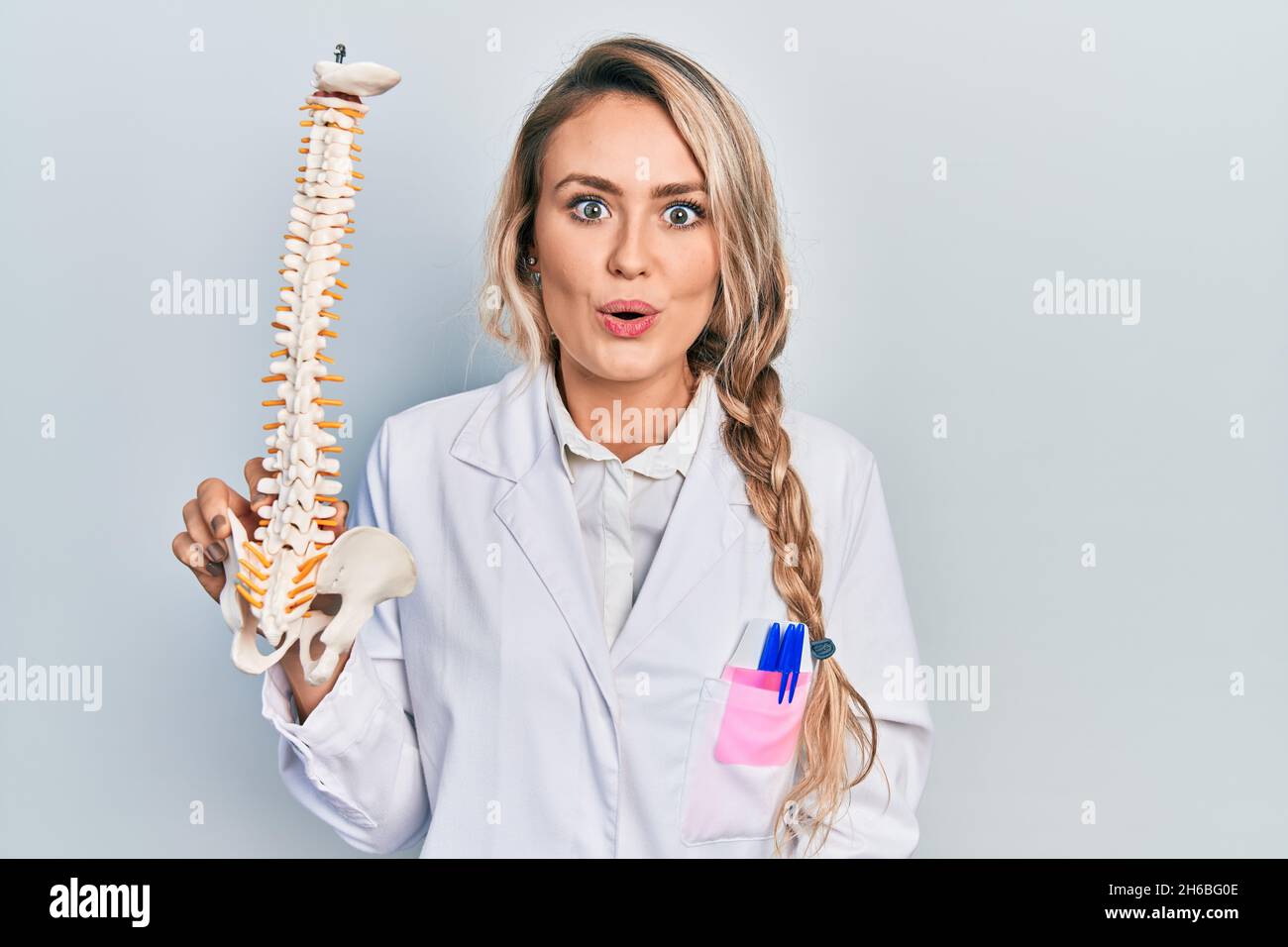 Beautiful young blonde doctor woman holding anatomical model of spinal ...