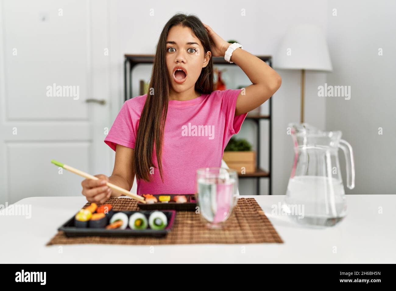 Young brunette woman eating sushi using chopsticks crazy and scared ...