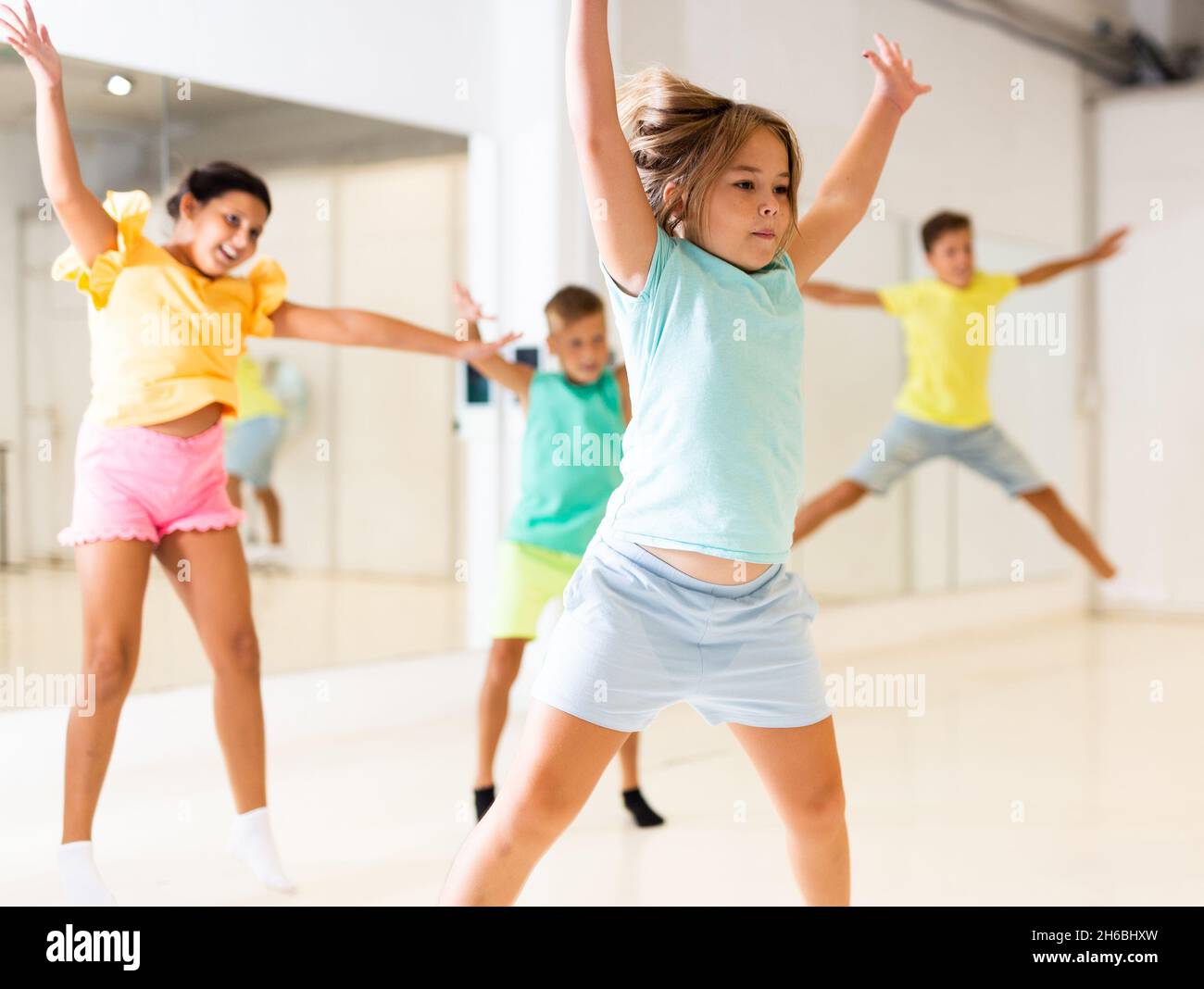 Happy tween girl jumping together with children in choreographic studio ...
