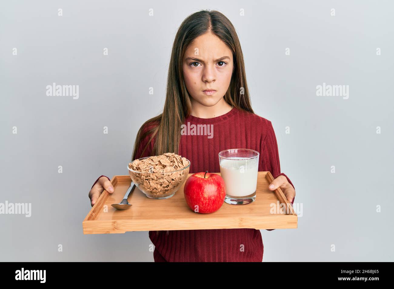 Beautiful brunette little girl holding tray with breakfast food skeptic ...