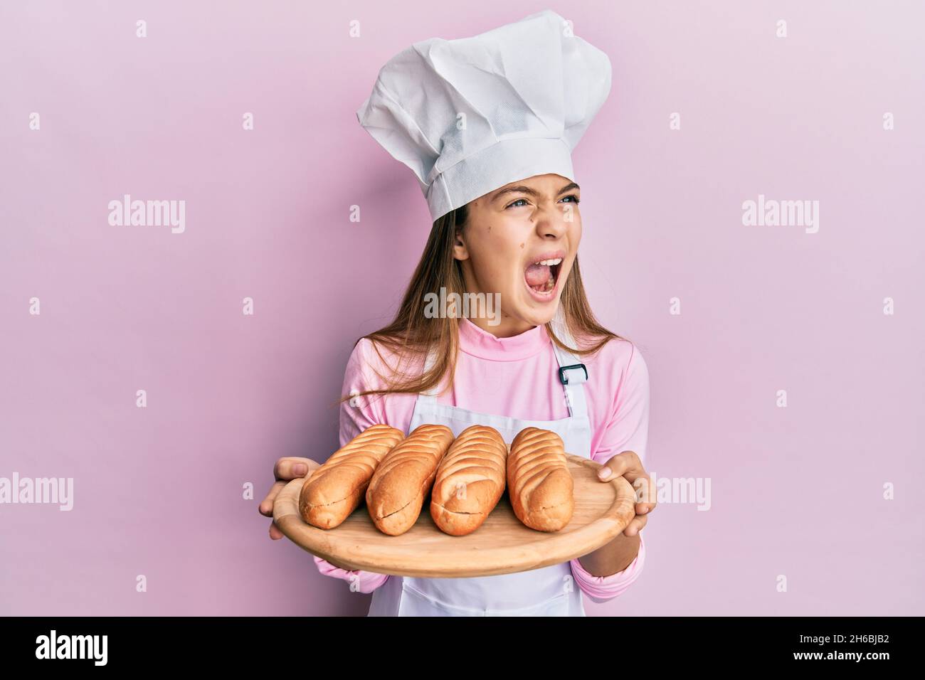 Beautiful brunette little girl wearing baker uniform holding homemade ...