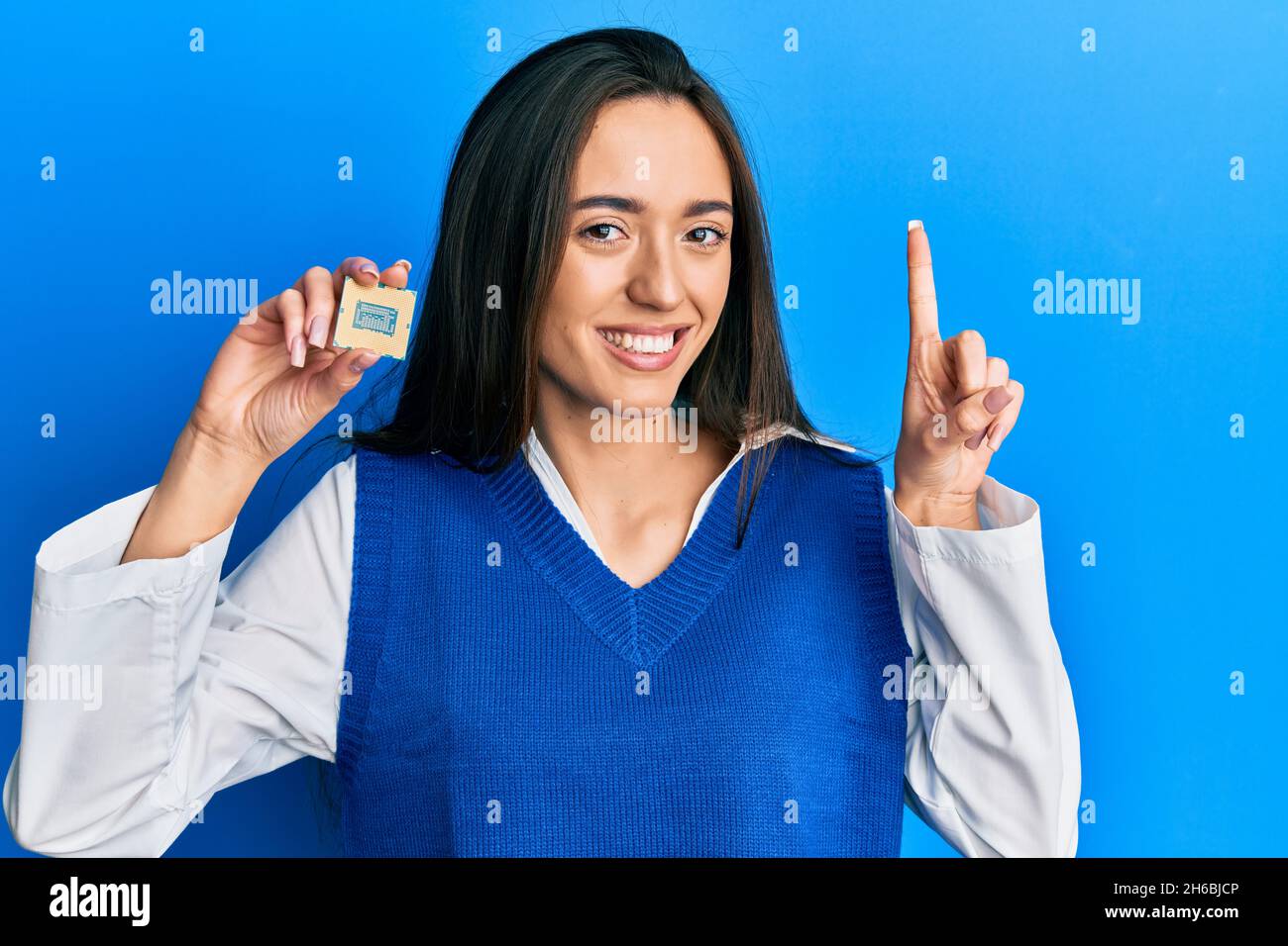 Young hispanic girl holding cpu computer processor smiling with an idea ...
