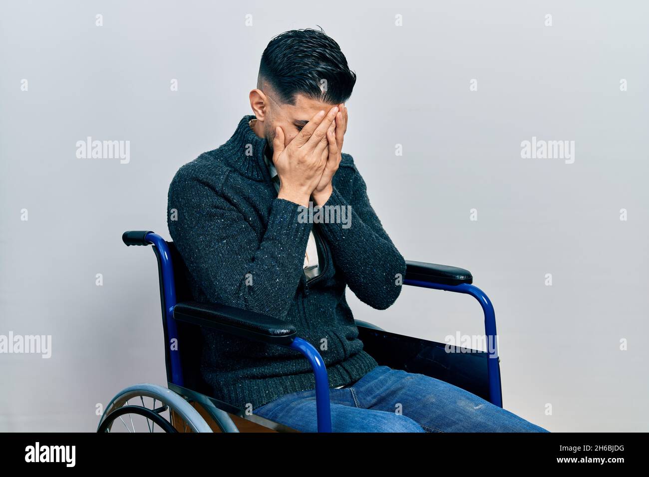 Handsome man with beard sitting on wheelchair with sad expression ...