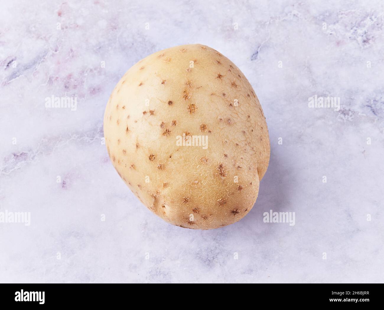 SIngle potato on a marble surface Stock Photo - Alamy