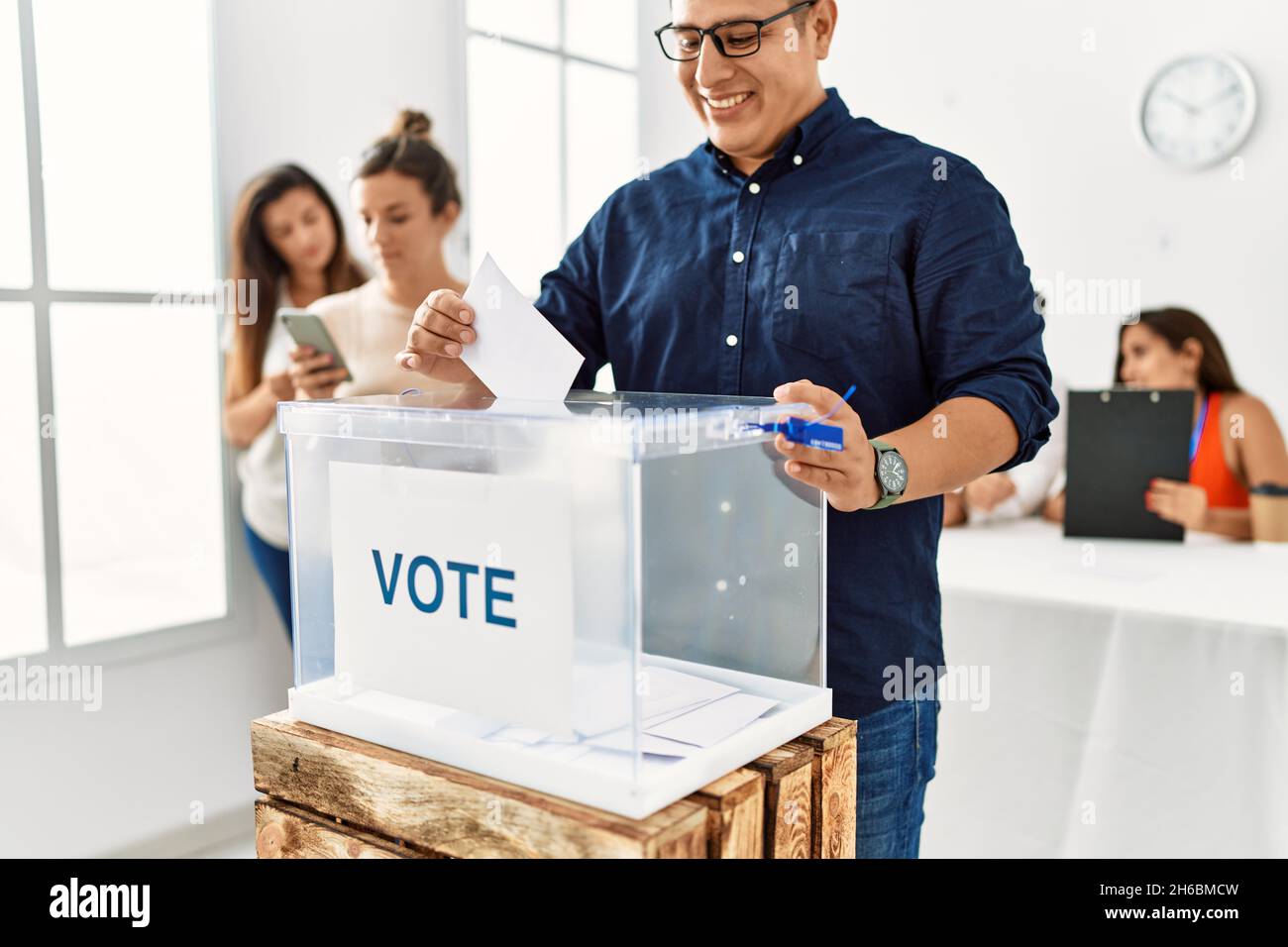 Young voter man smiling happy putting vote in voting box standing by ...
