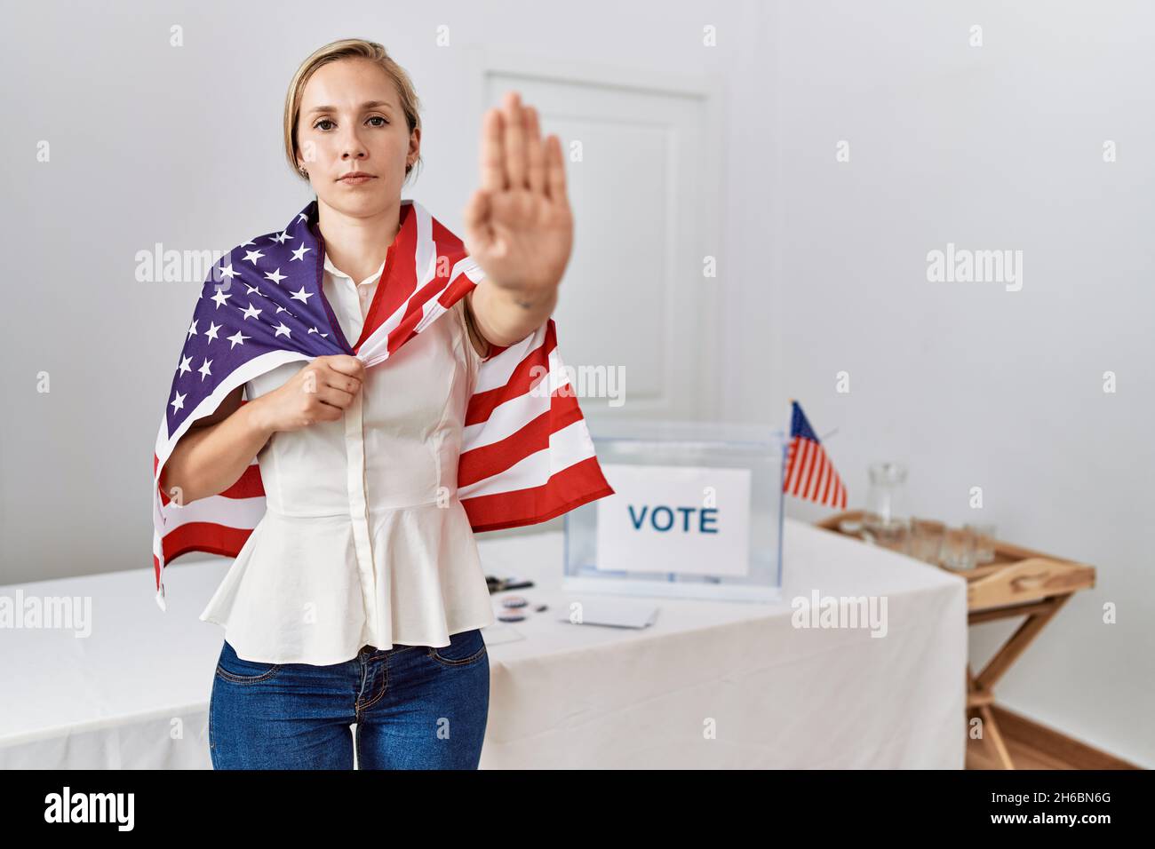 Young blonde woman at political campaign election holding usa flag with ...