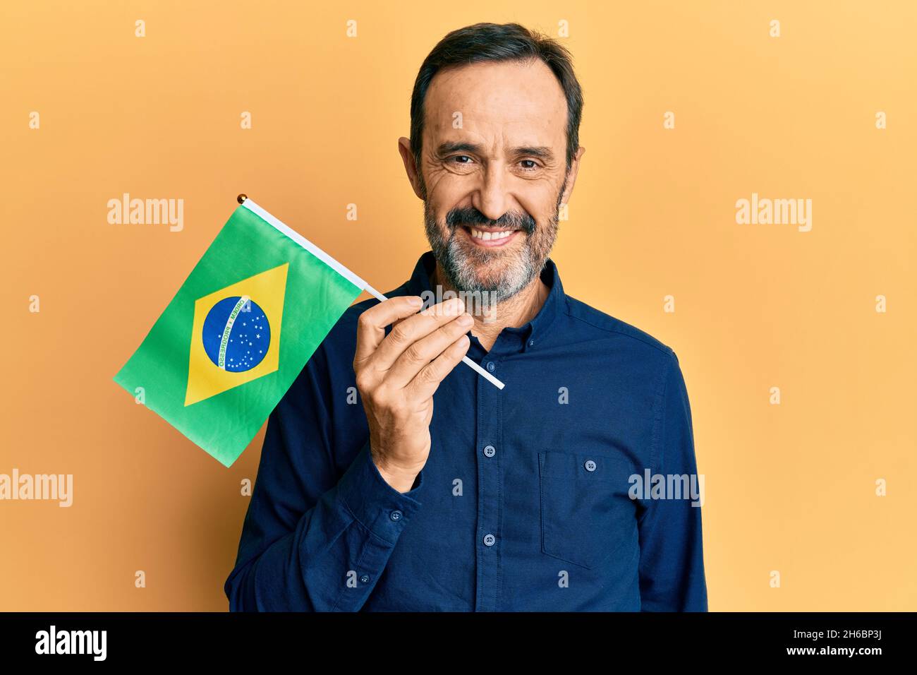 Middle age hispanic man holding brazil flag looking positive and happy ...