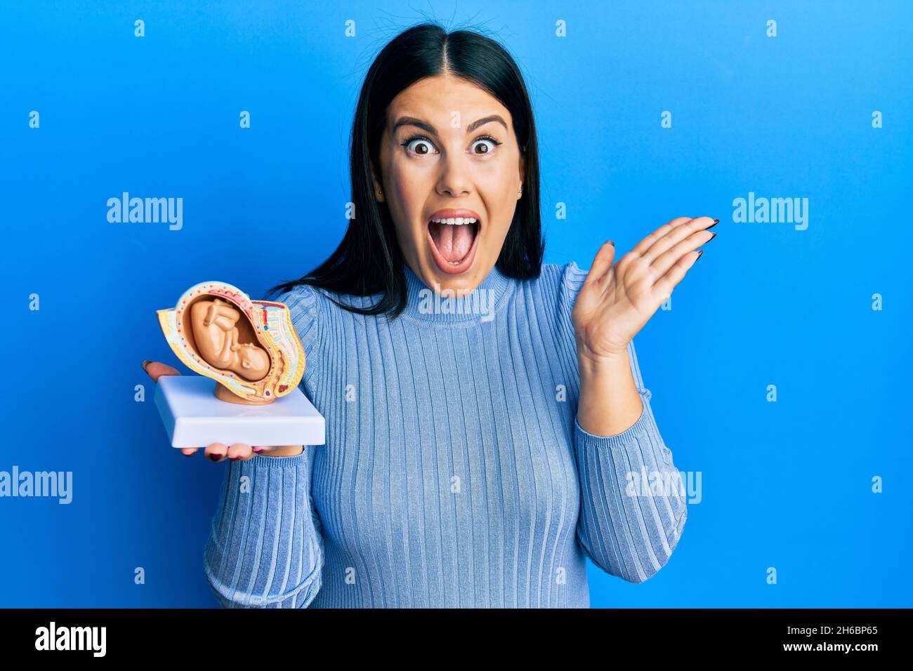 Beautiful brunette woman holding anatomical model of female uterus with ...
