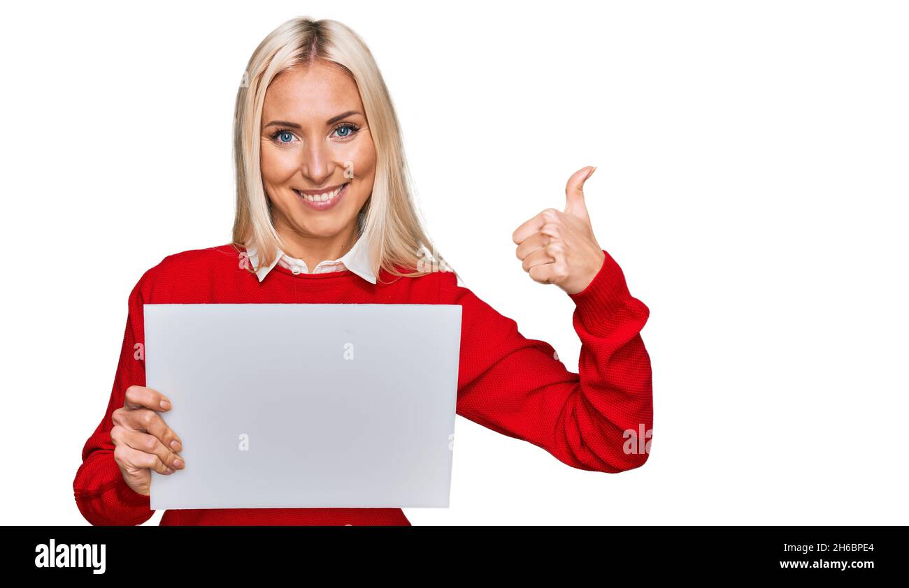 Young blonde woman holding blank empty banner smiling happy and ...