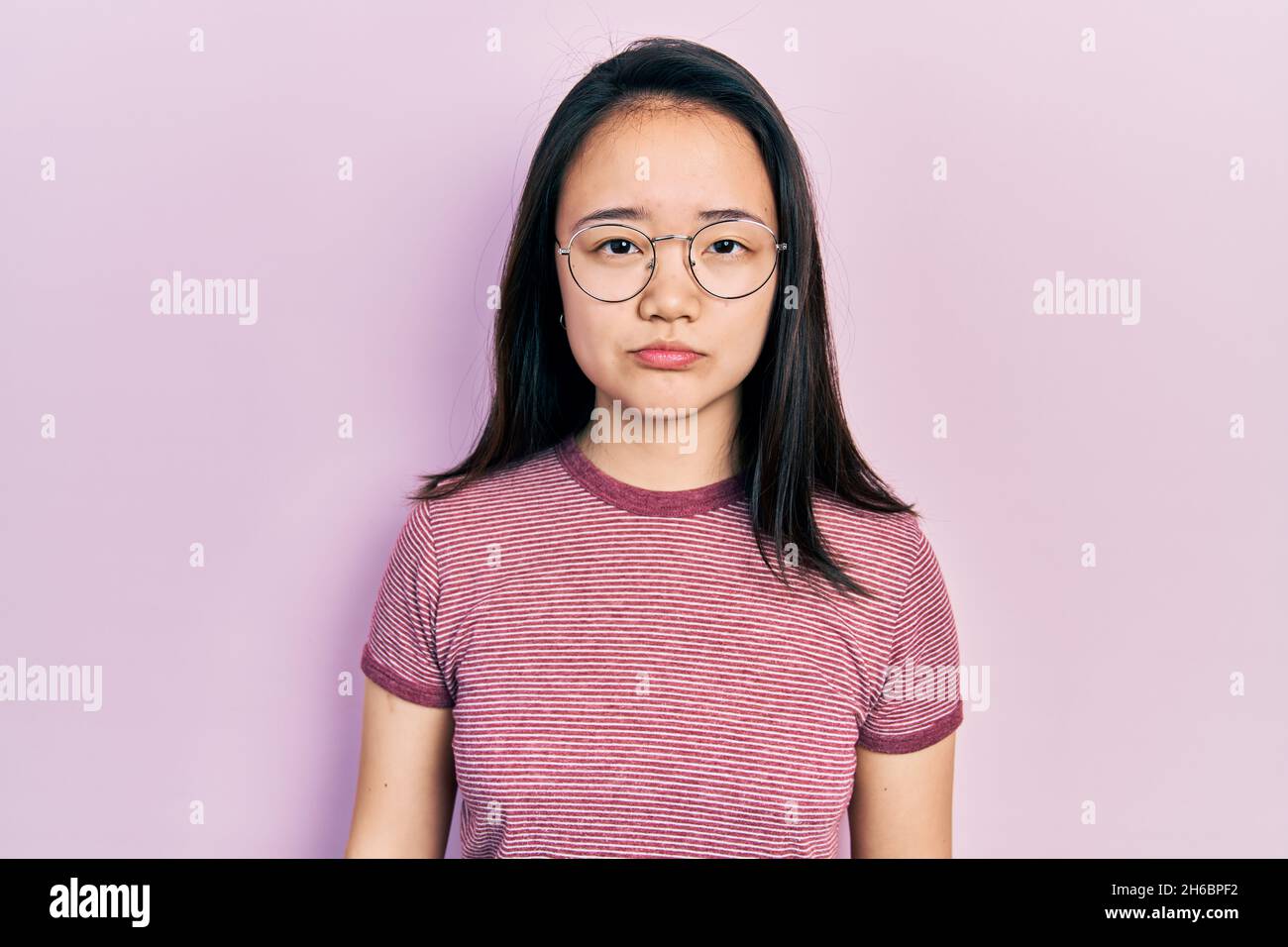 Young chinese girl wearing casual clothes and glasses depressed and ...