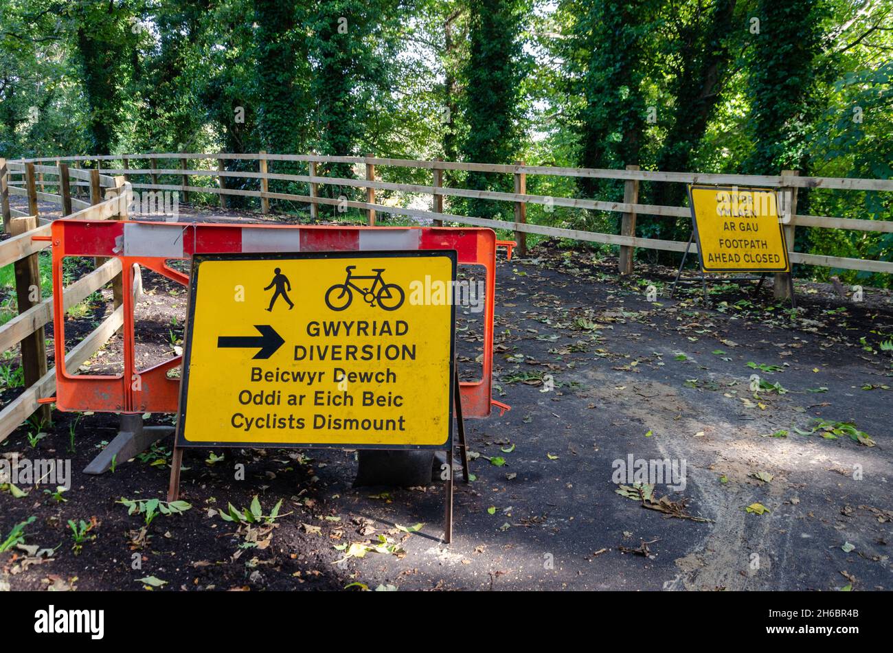 Two yellow signs placed outdoors in English and Welsh saying 'Footpath ...