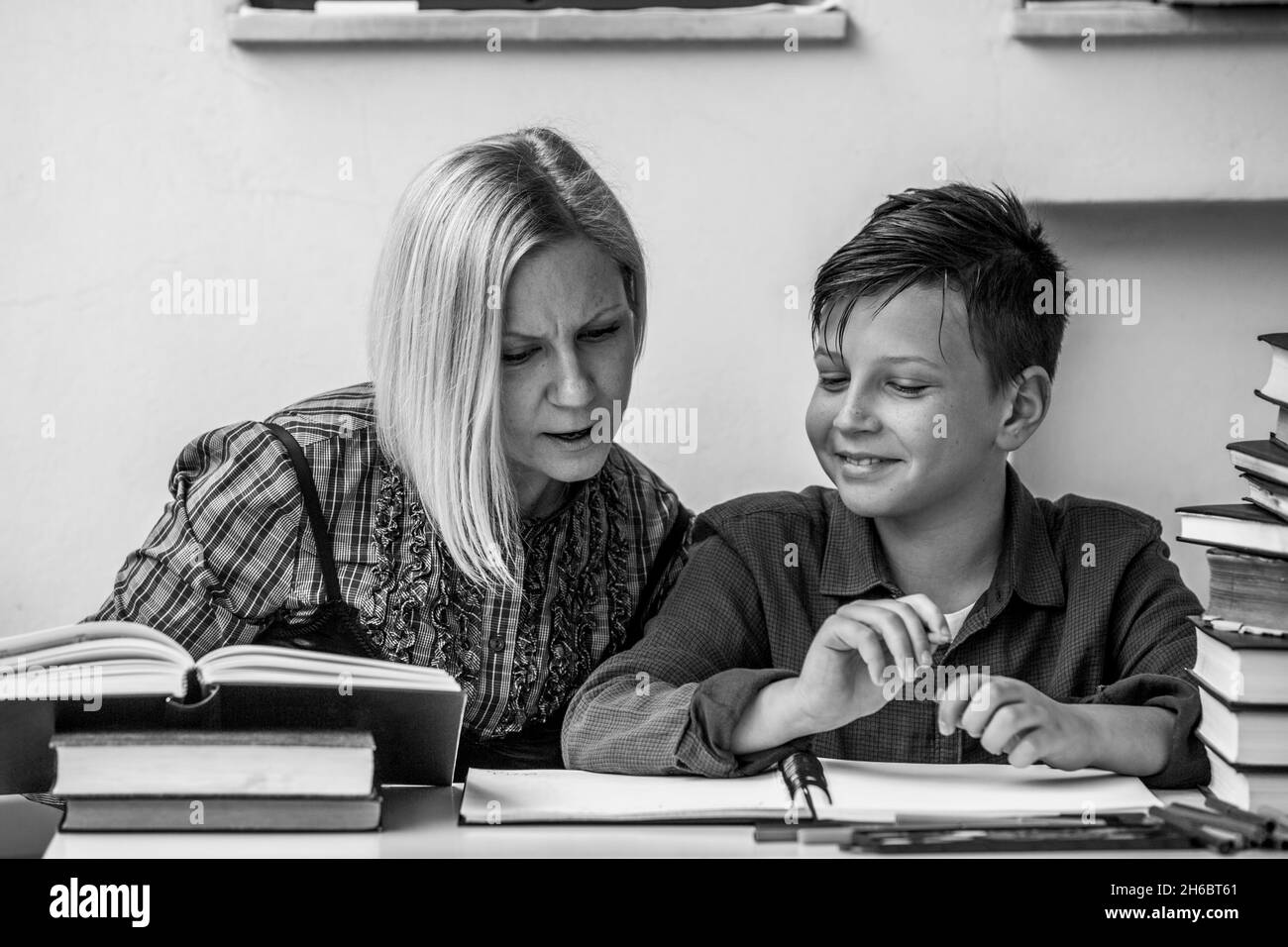 An elementary school boy doing homework with a tutor. Black and white ...
