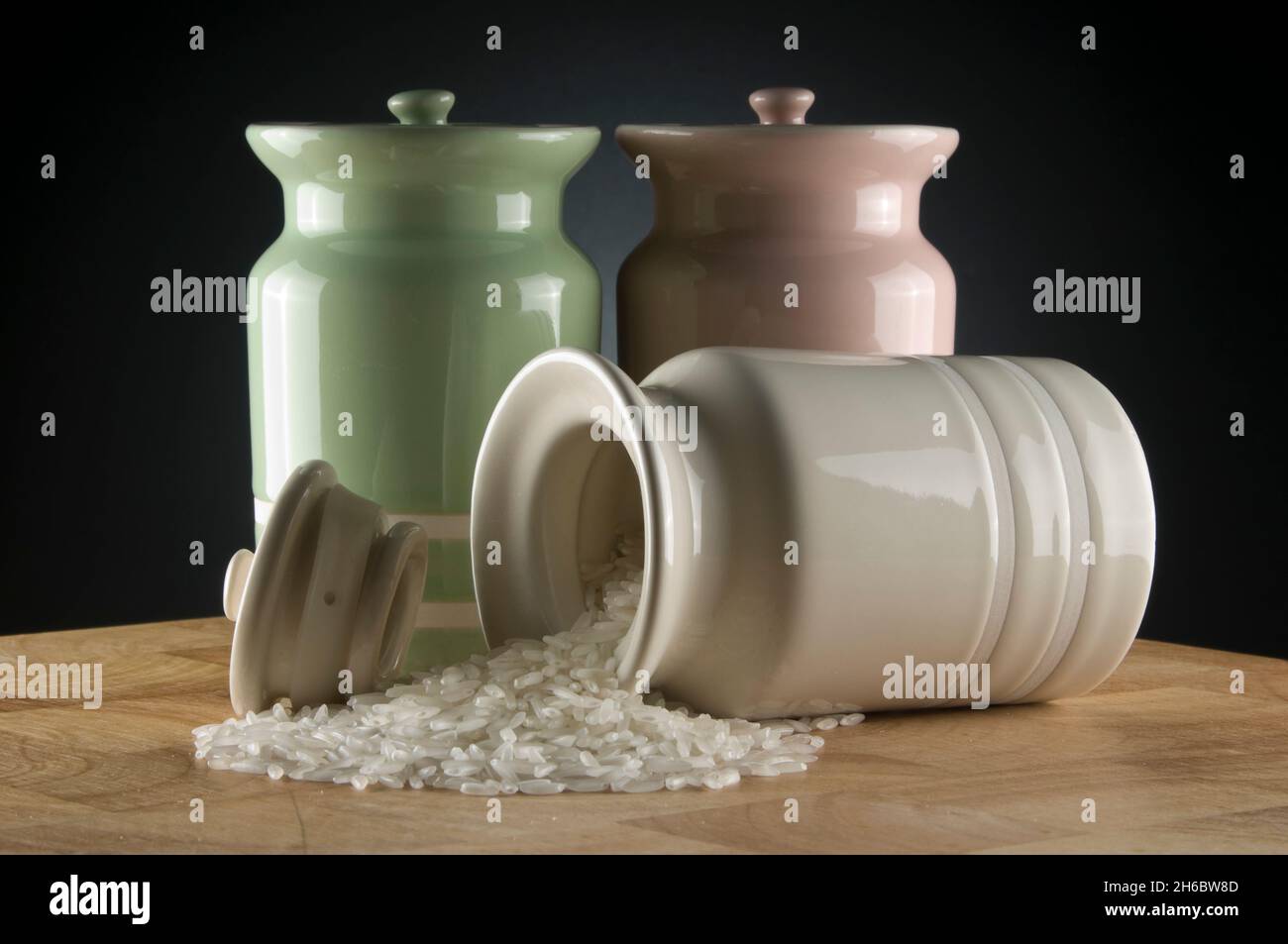 Ceramic canisters, one lying on its side on wood bench with rice ...