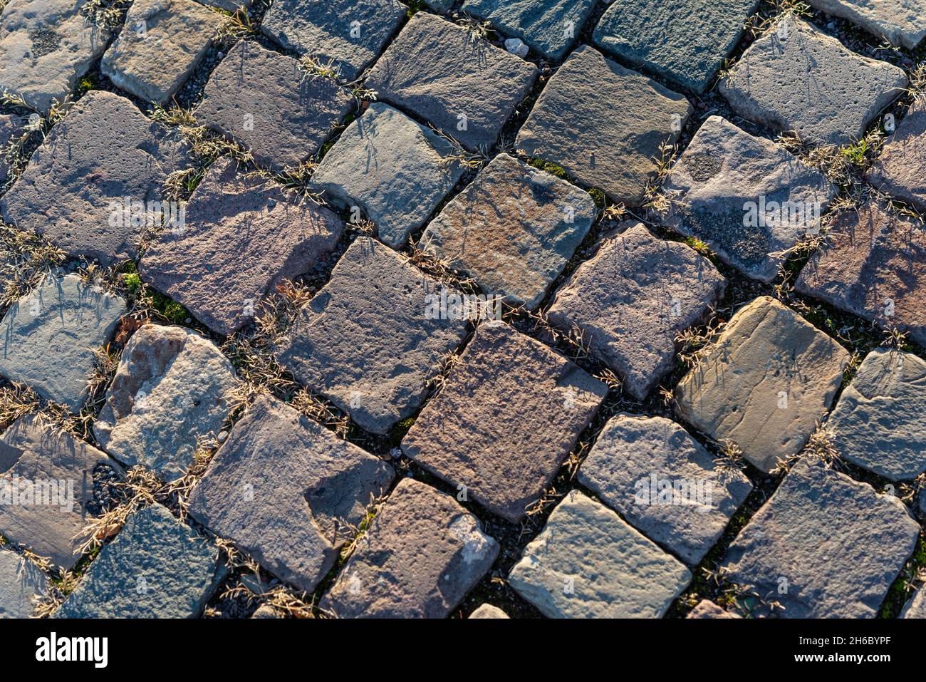 A top view of an empty old uneven cobblestone street pavement under ...