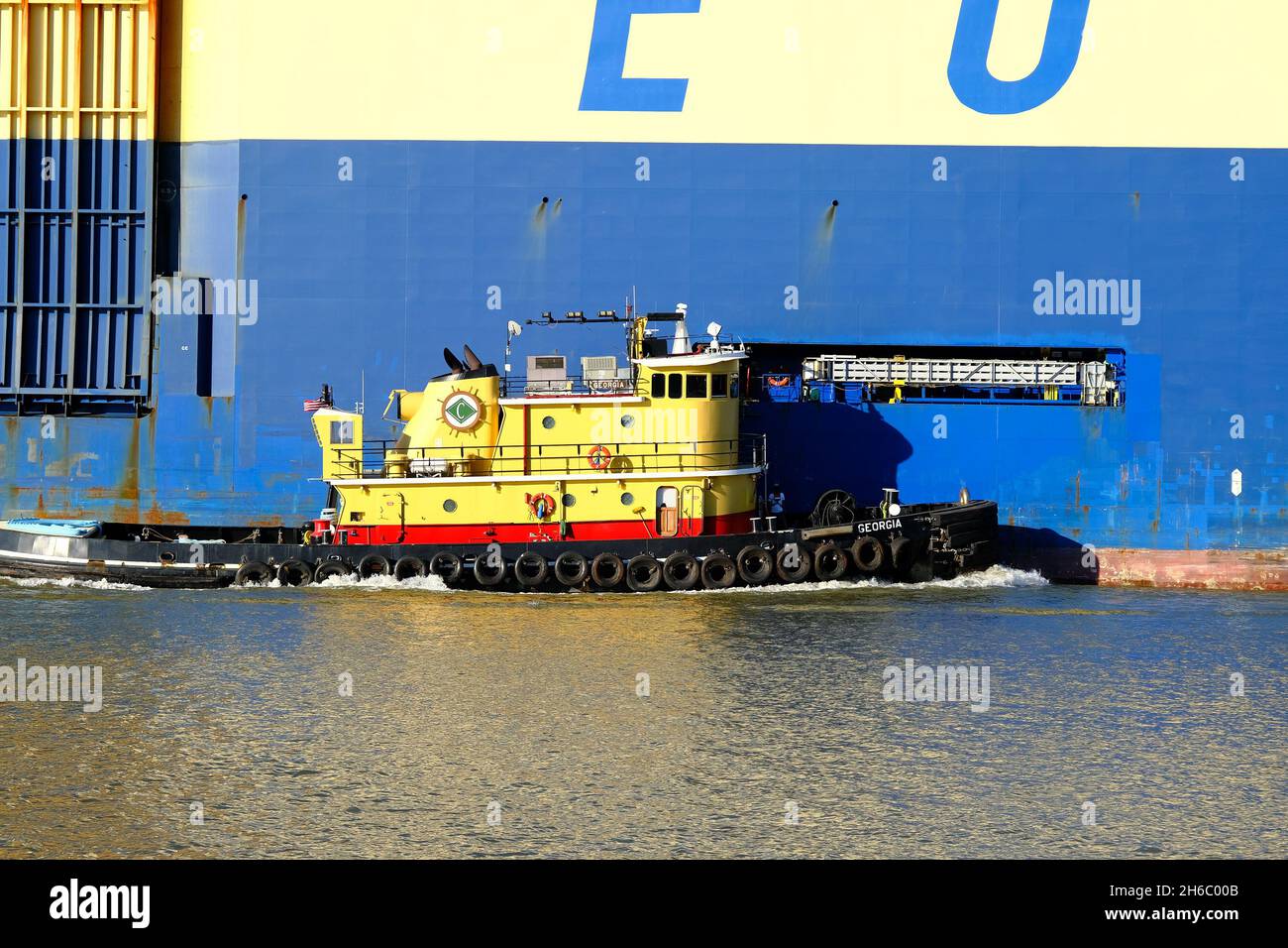 Tugboat Pushing Massive Freighter Stock Photo - Alamy