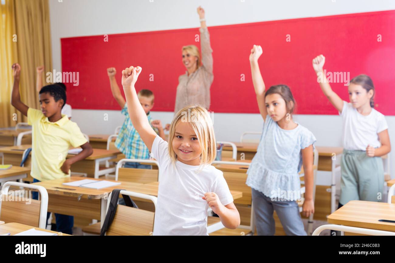 Teacher conducts gymnastics for elementary school children in classroom ...