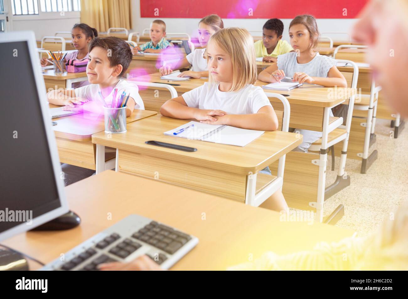 Preteen schoolchildren diligently working in class with teacher Stock ...