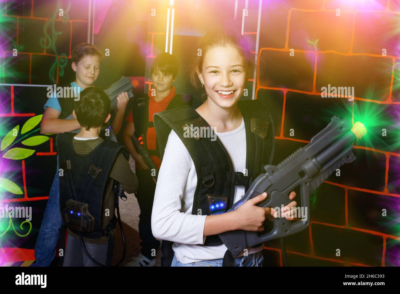 Cheerful teen girl standing with laser pistol in dark lasertag r Stock ...