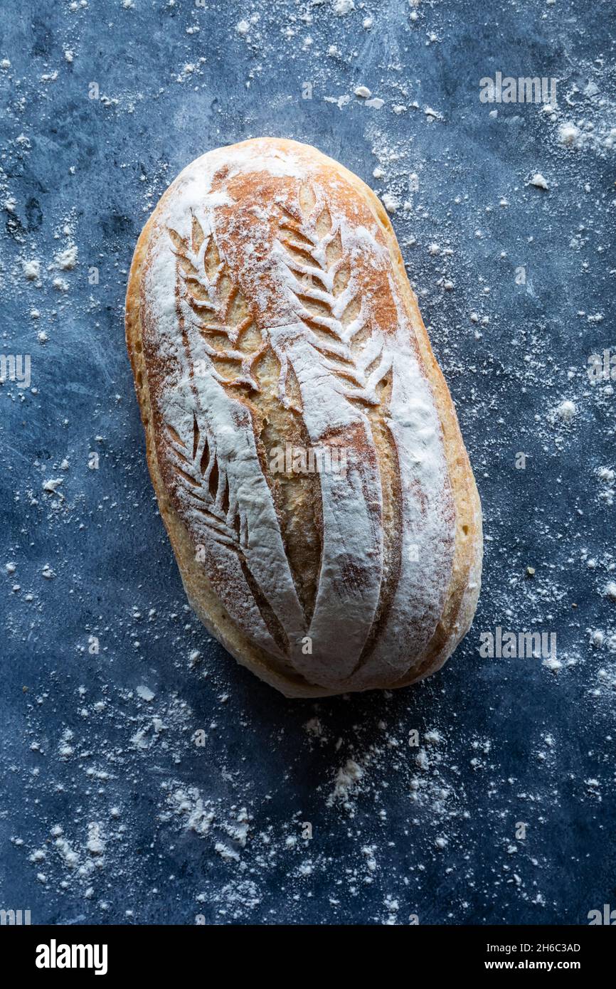 Top down view of a whole loaf of sourdough bread on a dark wooden table ...