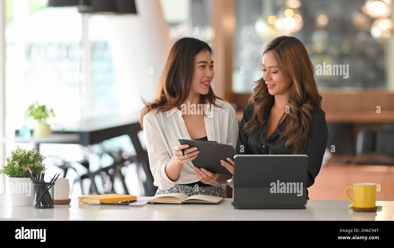 Businesswomen discussing work in office. Happy two colleagues friends ...