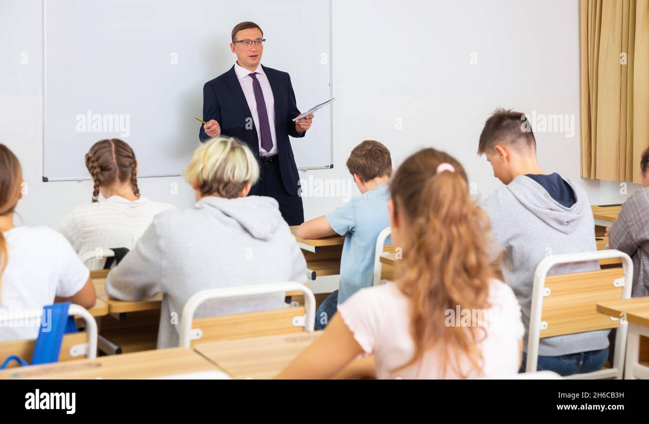 Man teacher with notebook is giving interesting lecture for students in ...