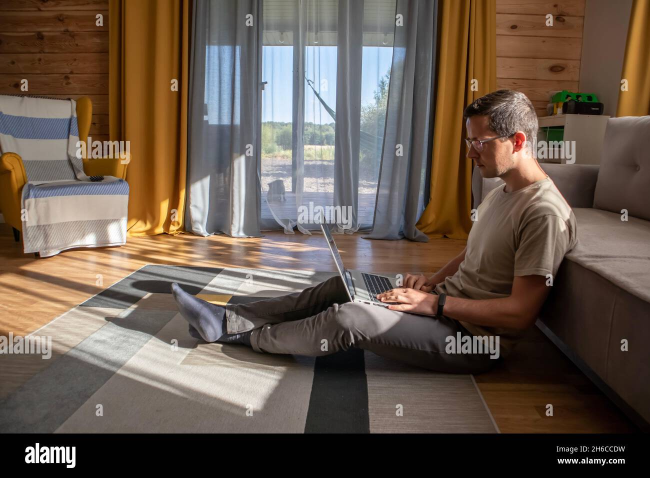 Comfortable work from home. A man is sitting and working on the floor ...
