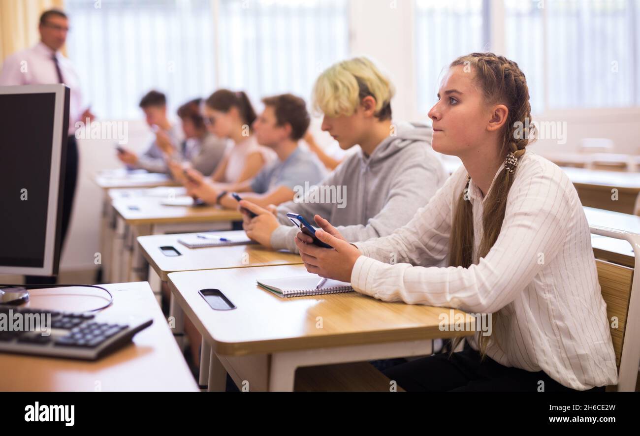 Teenage students using smartphones during lesson Stock Photo - Alamy