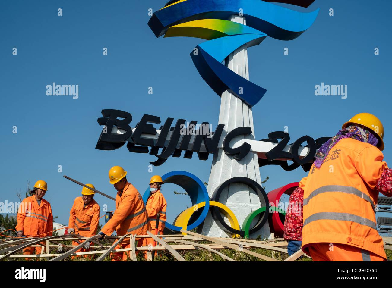 Urban ecological workers work in front of a huge emblem of Beijing 2022 ...