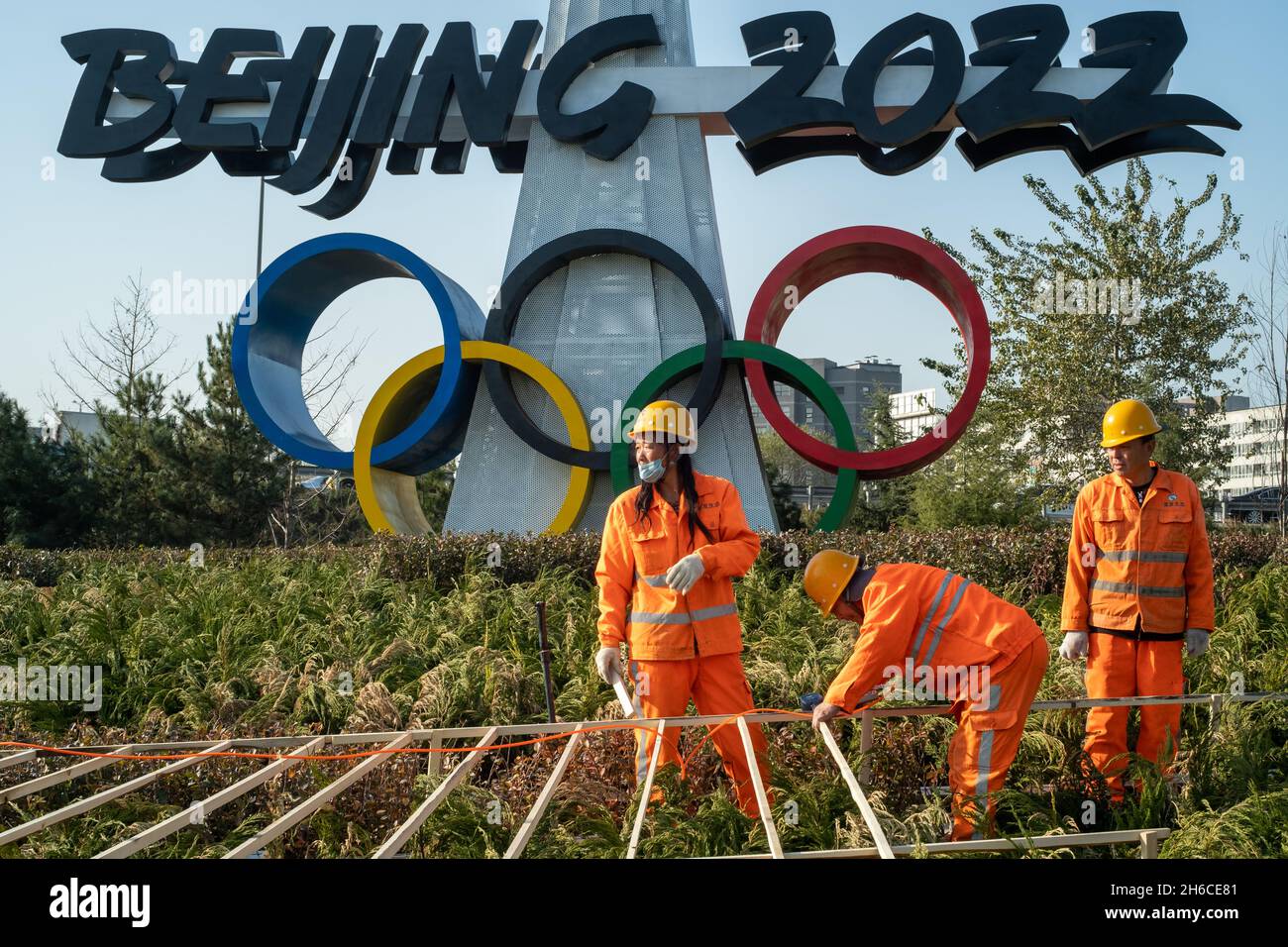 Urban ecological workers work in front of a huge emblem of Beijing 2022 ...