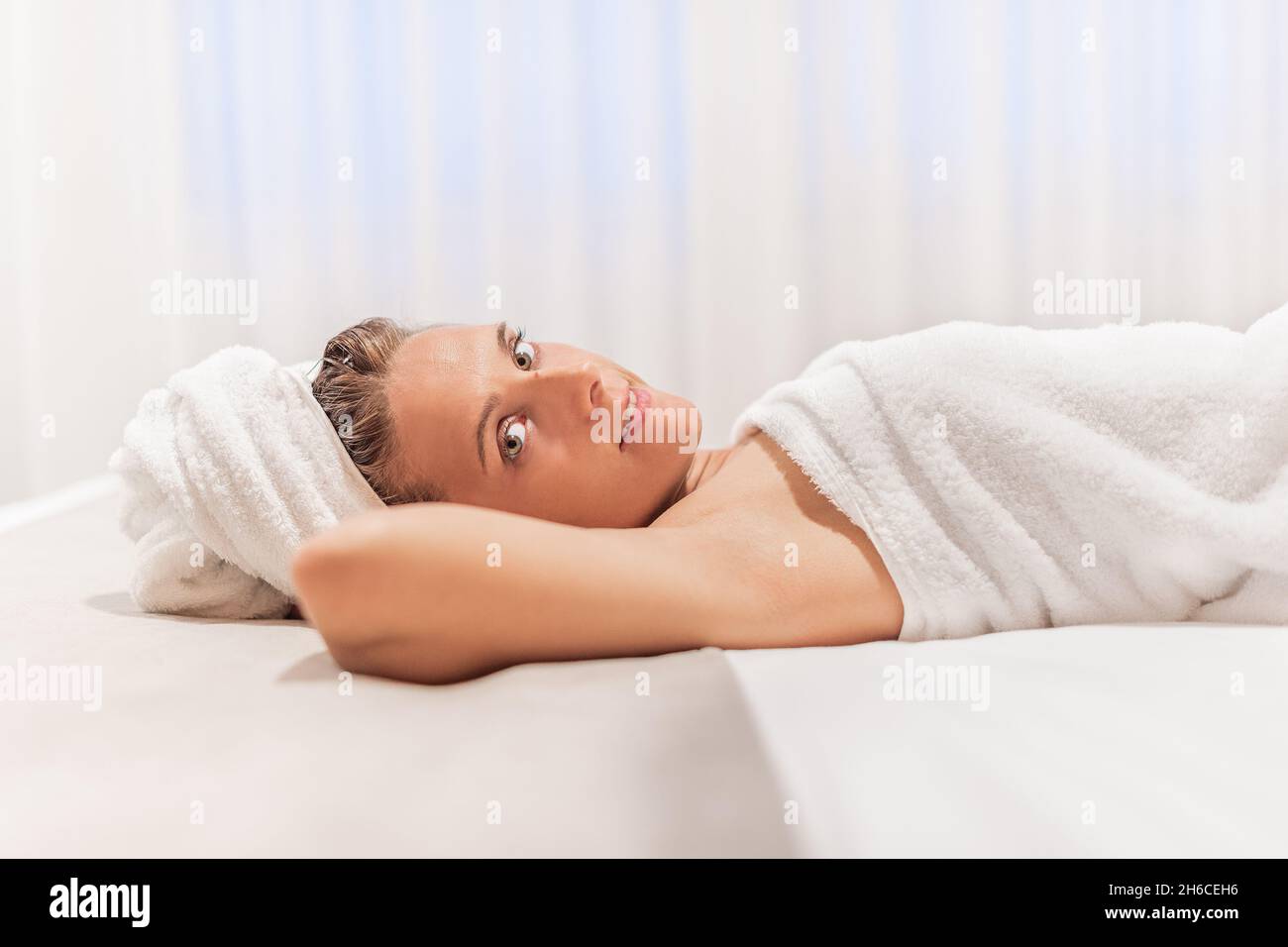 Woman after showering lying in bed and looking at camera Stock Photo ...