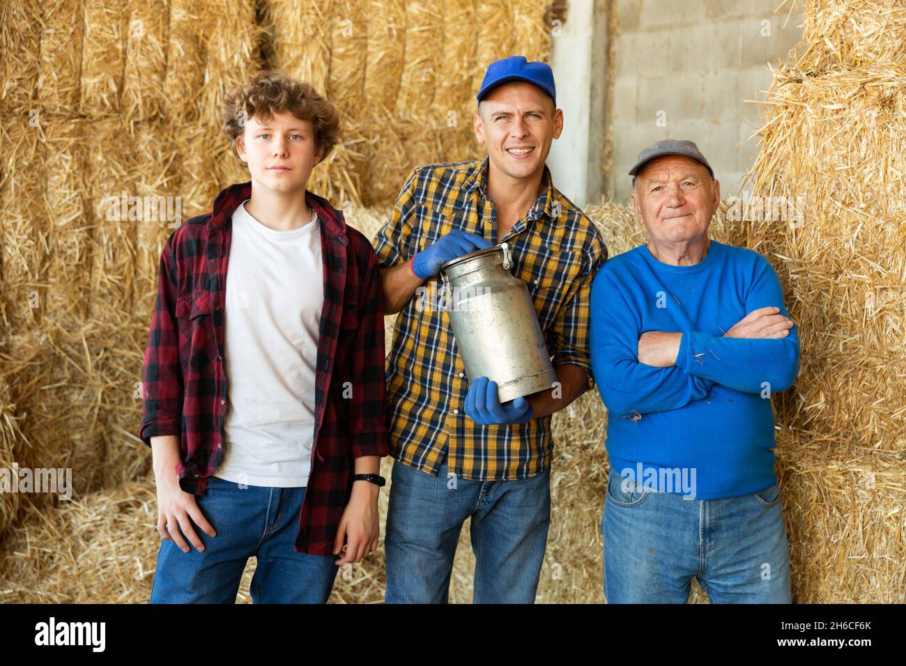Portrait of farmers of different generations against background of hay ...